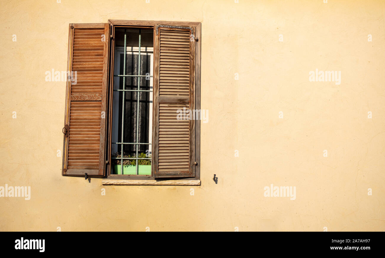 Old vintage window with shutters on the yellow facade of the house ...