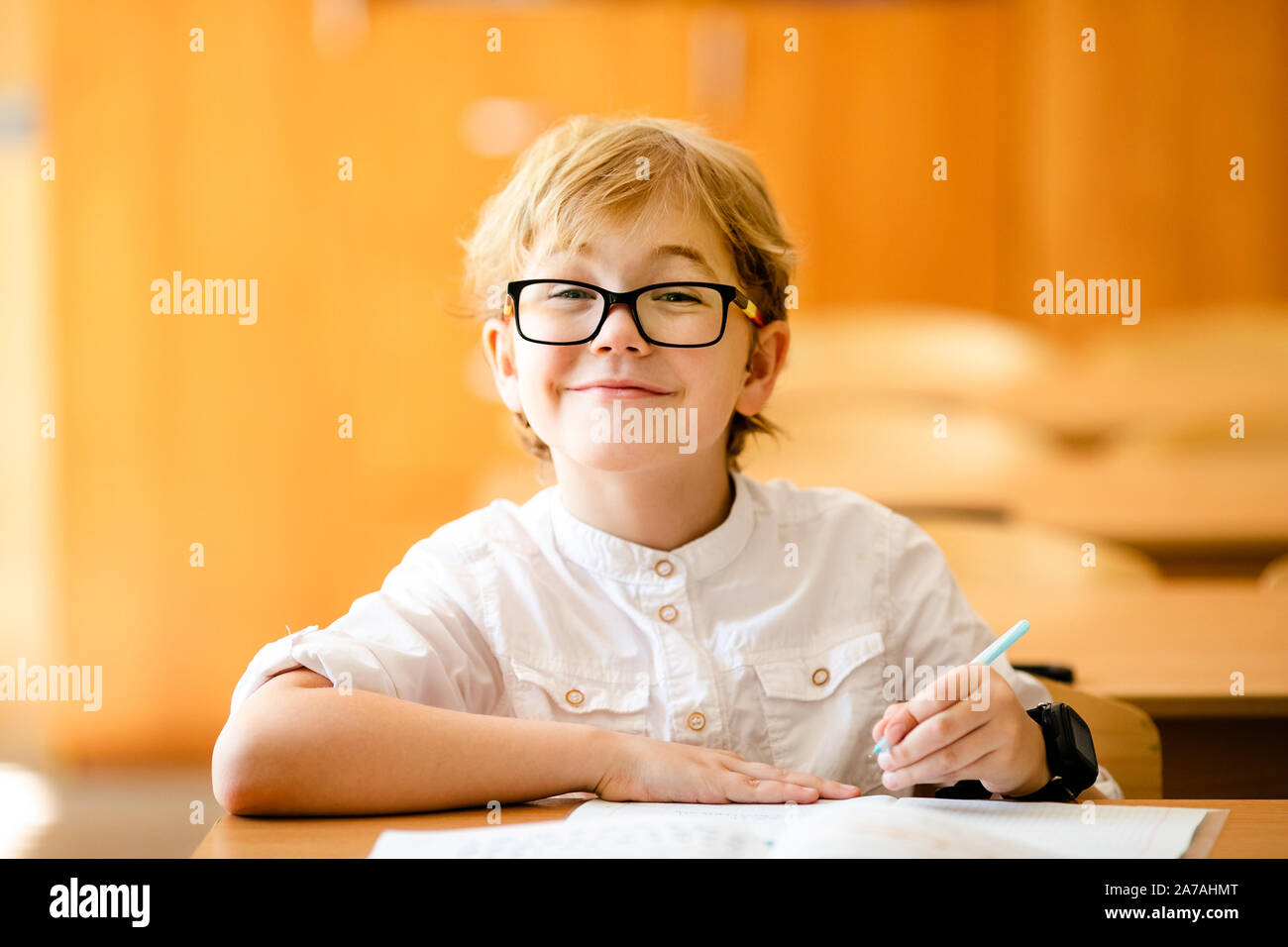 Seven years old child with glasses writing his homework at school. Boy ...