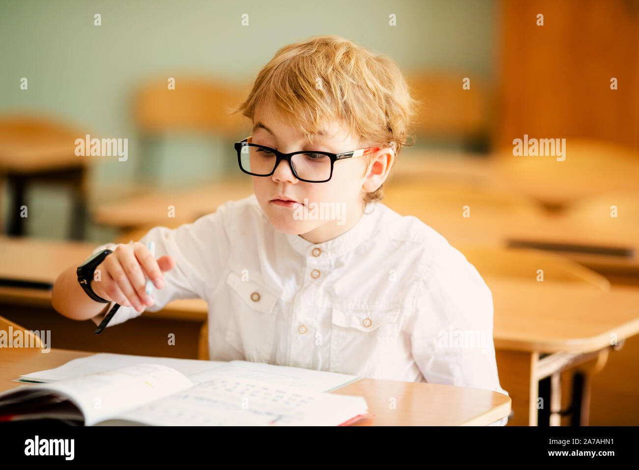 Seven years old child with glasses writing his homework at school. Boy ...