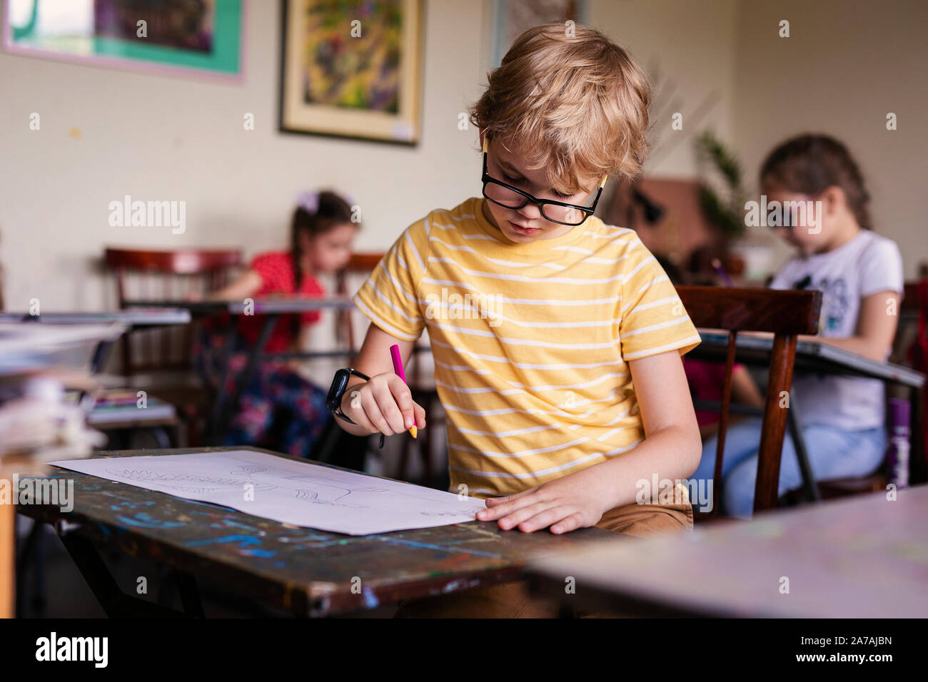 Blonde boy with glasses drawing. Group of elementary school pupils in ...