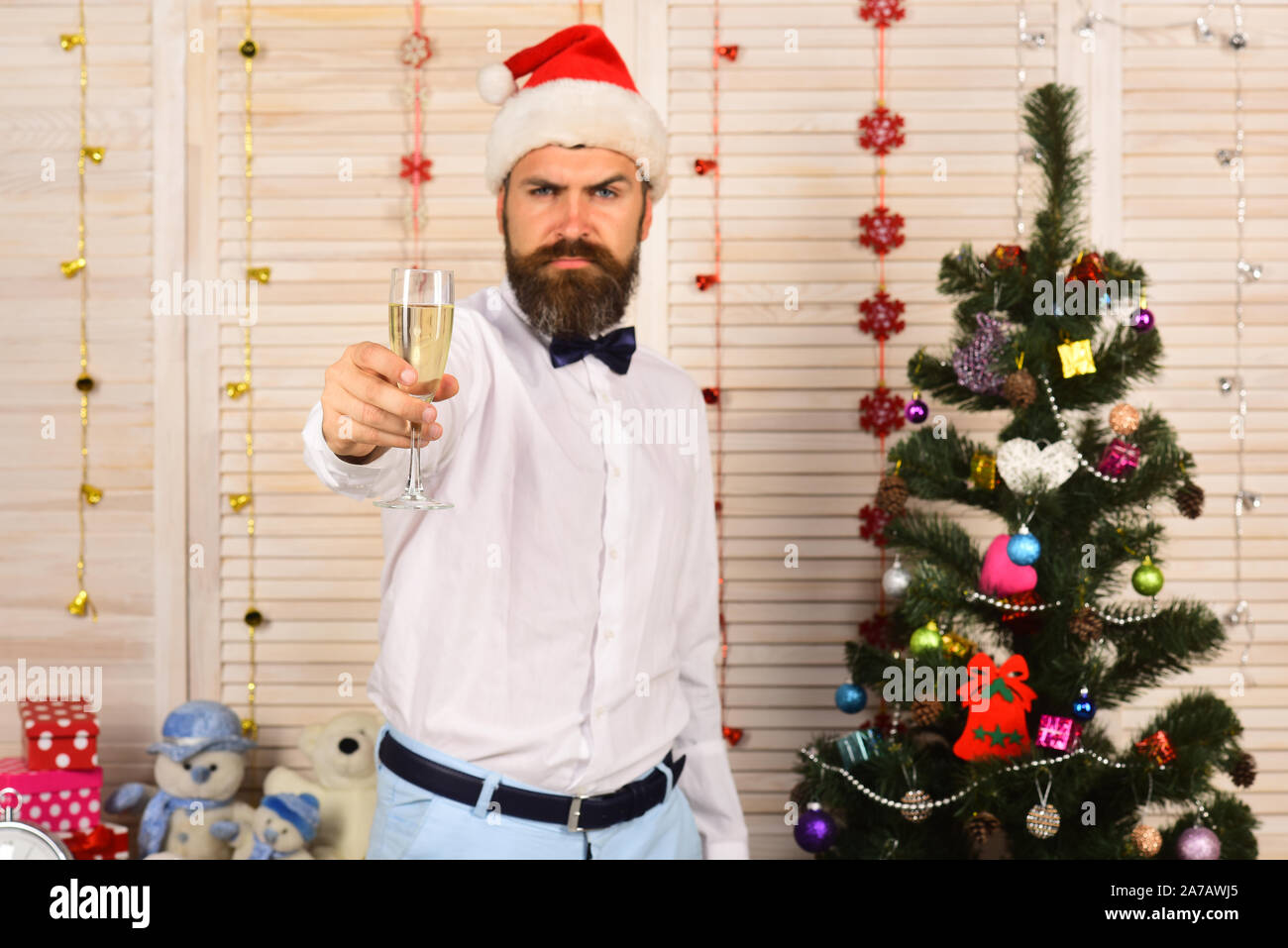 Celebration and cheers concept. Guy near Christmas tree on wooden wall ...