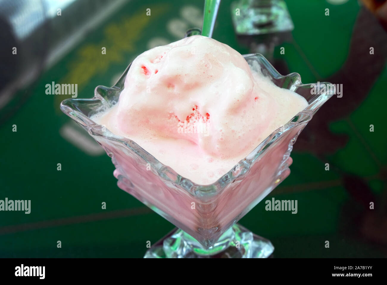 Pink strawberry ice cream top view. On the table is a glass vase with ...