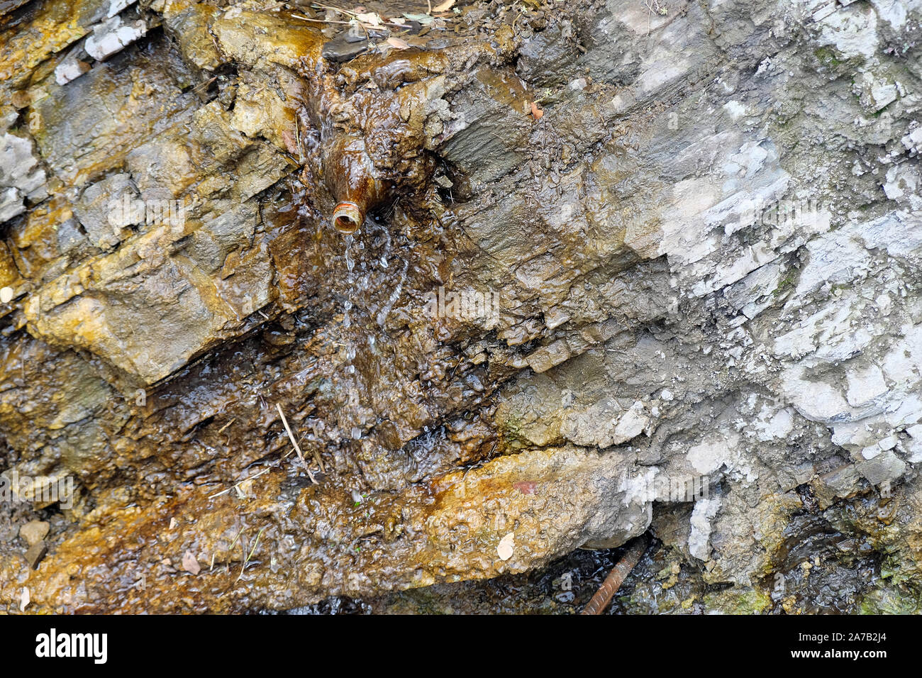 Surface of rocks wall with water flowing. Clear water flows from the ...