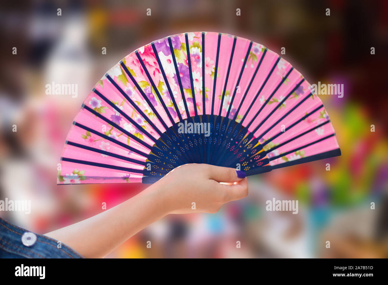 Hand holding fan on small shop with blur background Stock Photo - Alamy