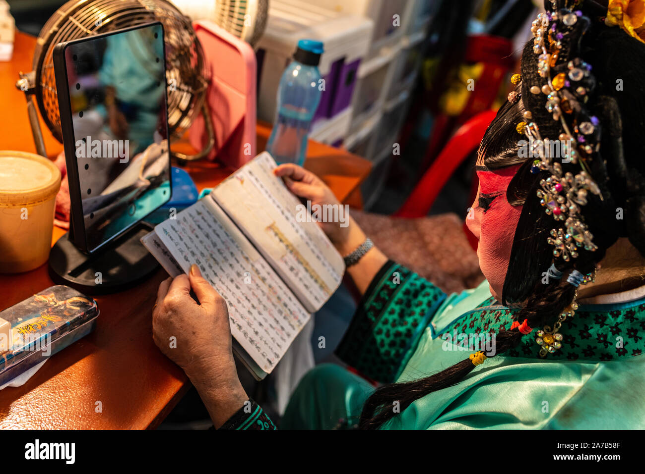Chinese opera artiste reading scripts at backstage before performance ...