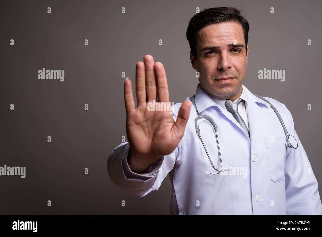 Handsome Persian man doctor against gray background Stock Photo - Alamy