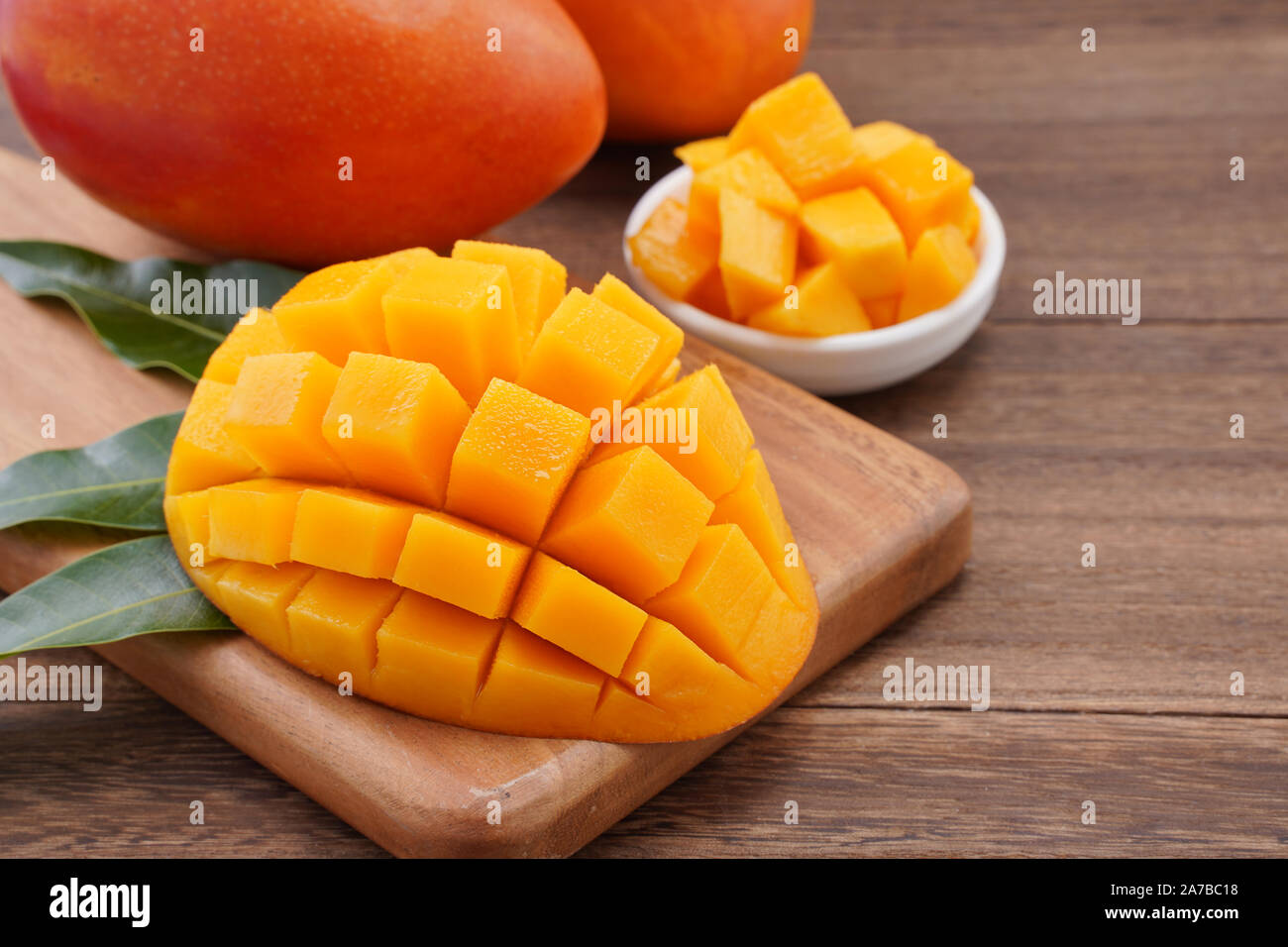 Fresh mango,beautiful chopped fruit with green leaves on dark wooden ...