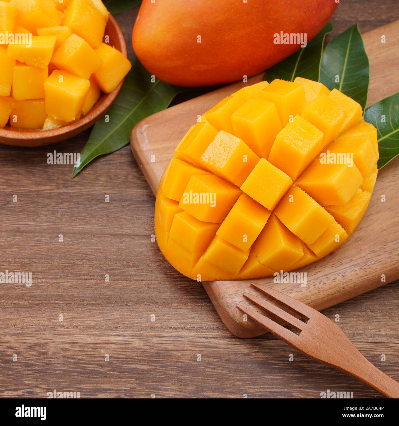 Fresh mango,beautiful chopped fruit with green leaves on dark wooden ...