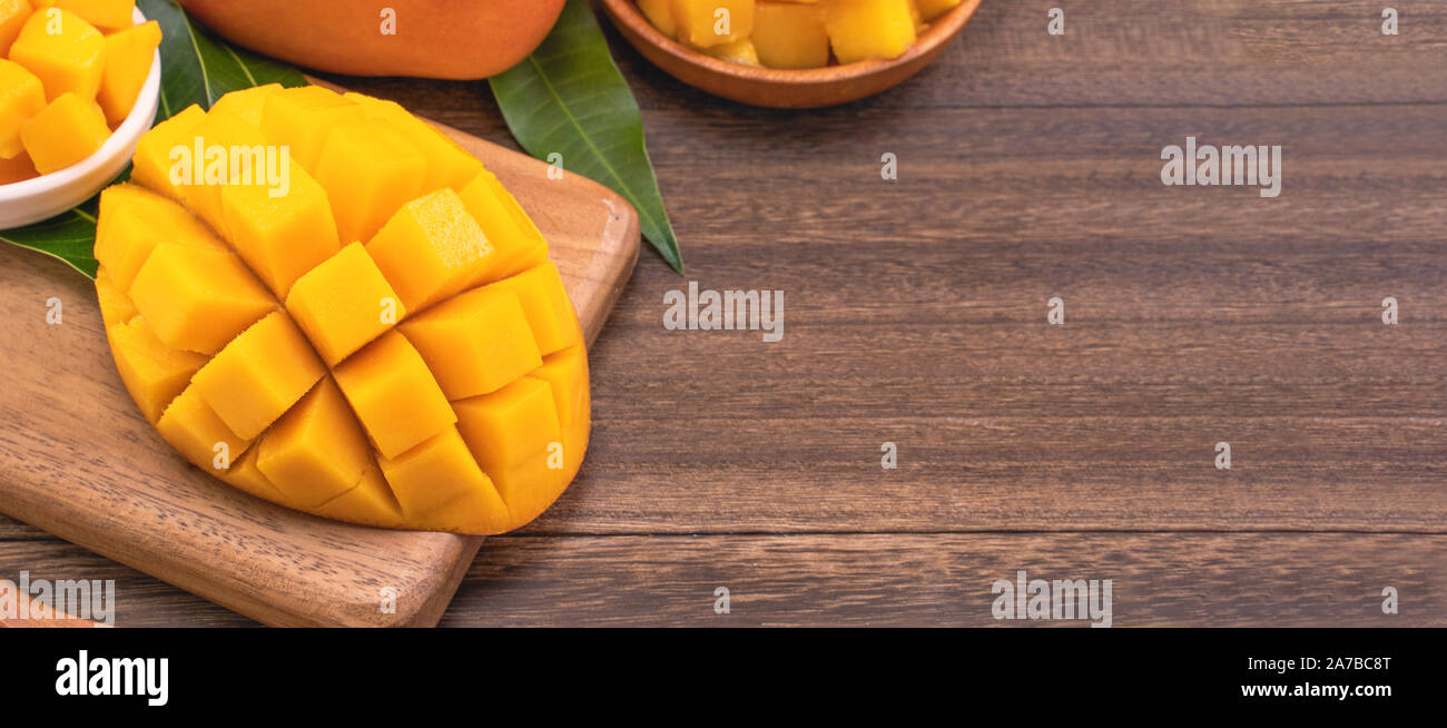 Fresh mango,beautiful chopped fruit with green leaves on dark wooden ...