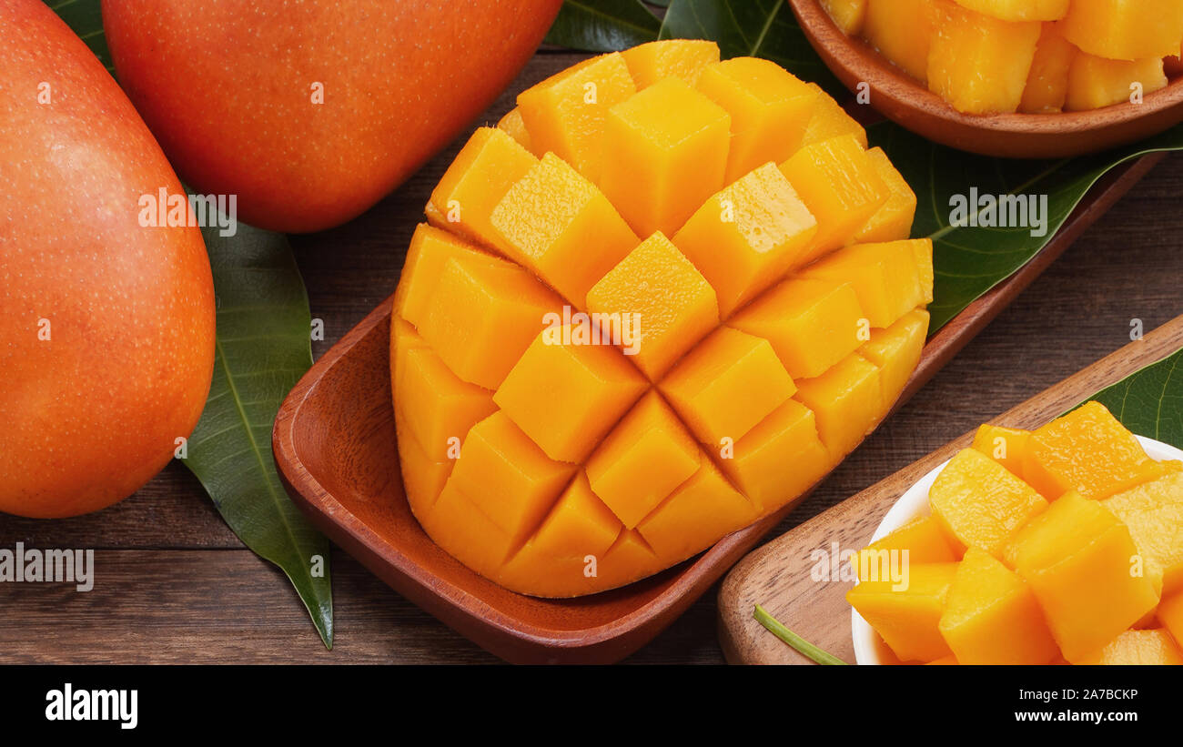 Fresh mango,beautiful chopped fruit with green leaves on dark wooden ...