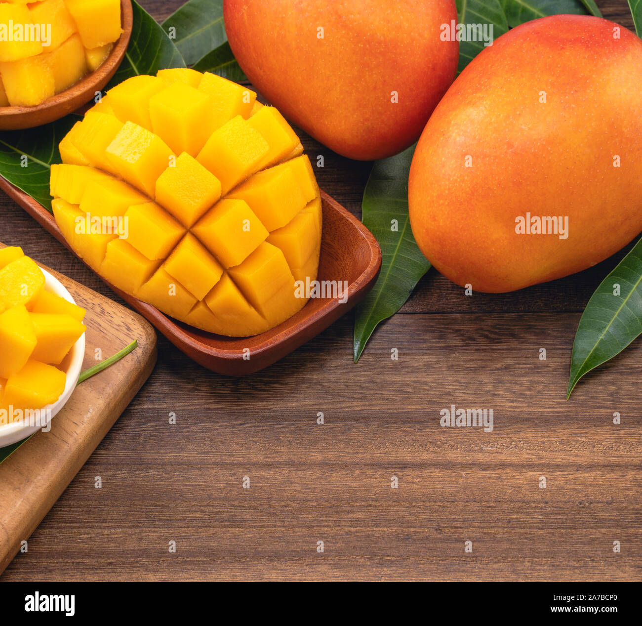 Fresh mango,beautiful chopped fruit with green leaves on dark wooden ...