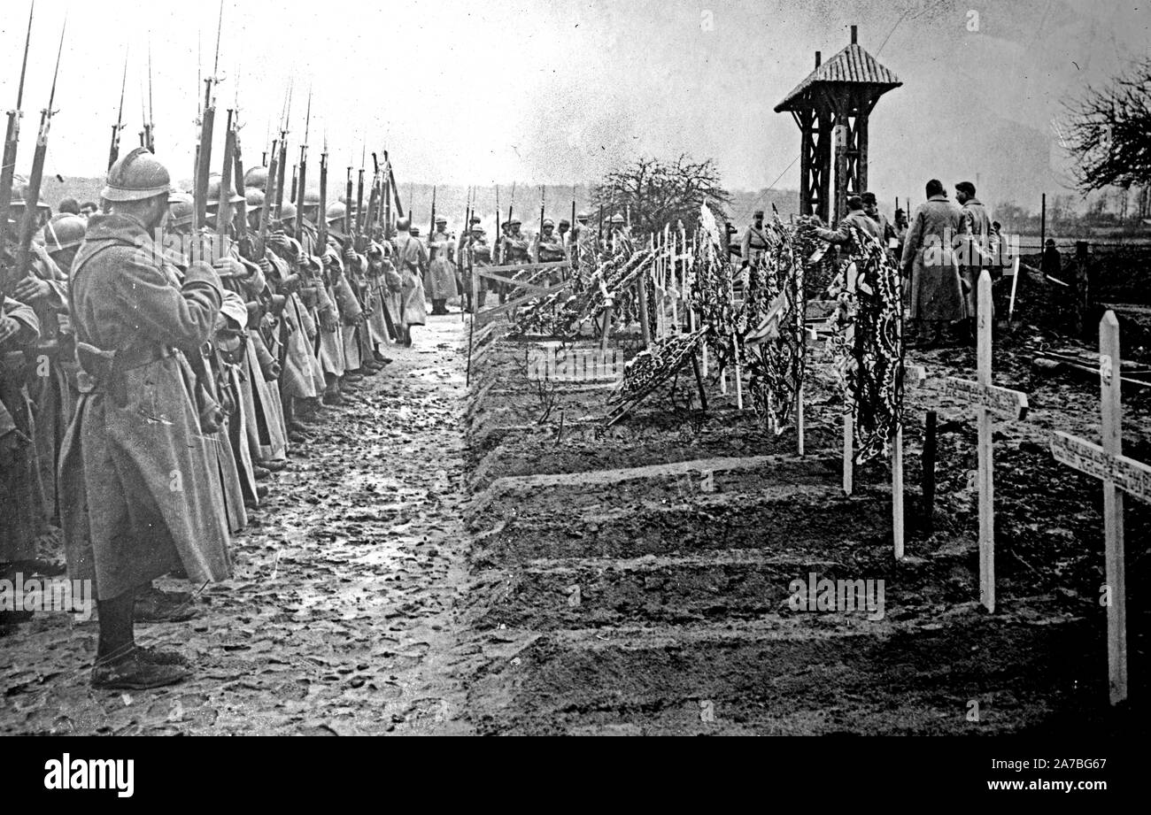 Photograph shows soldiers standing at graves during the burial of a ...