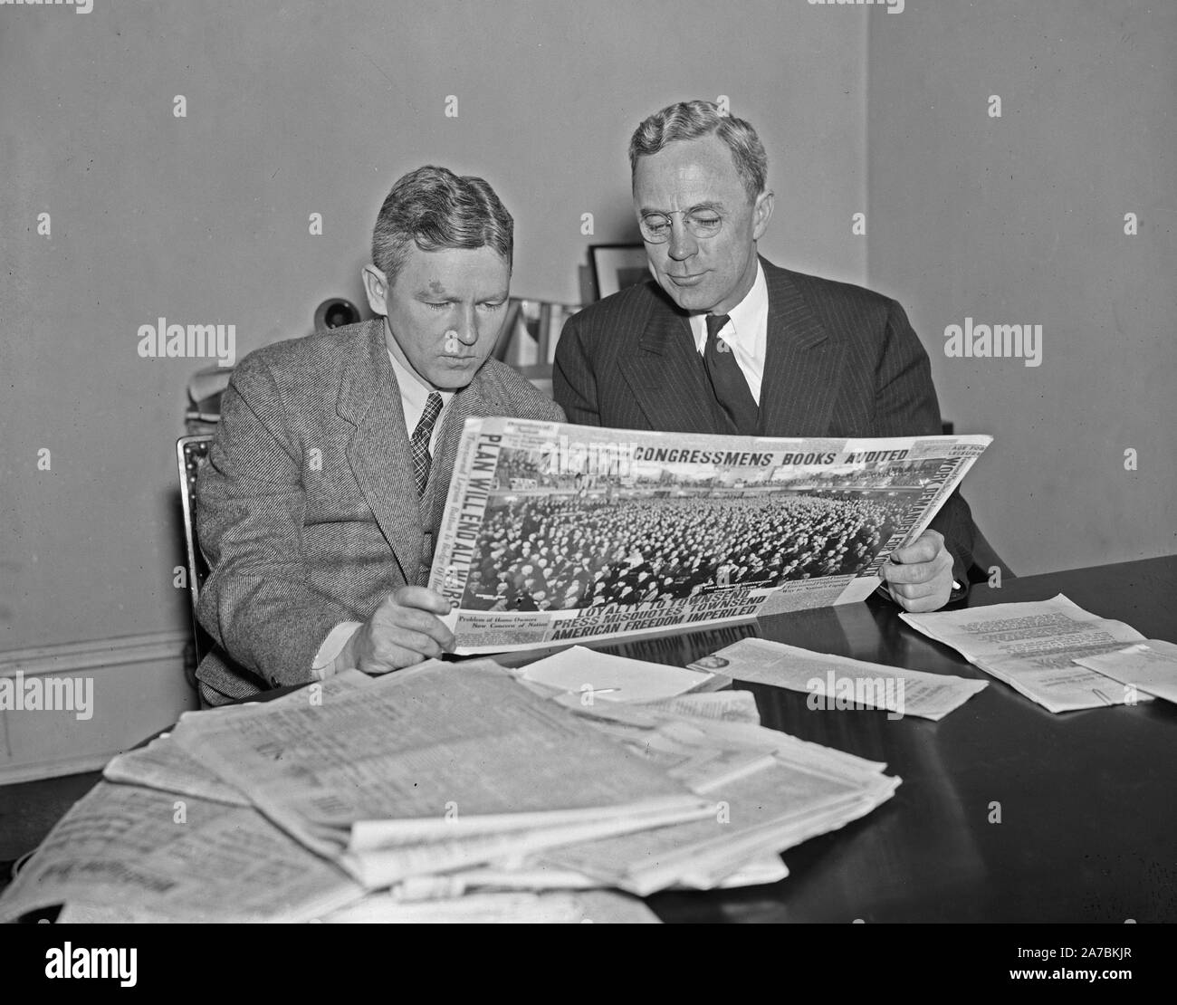 Two men sitting at a desk reading a newspaper ca. 1936 Stock Photo - Alamy