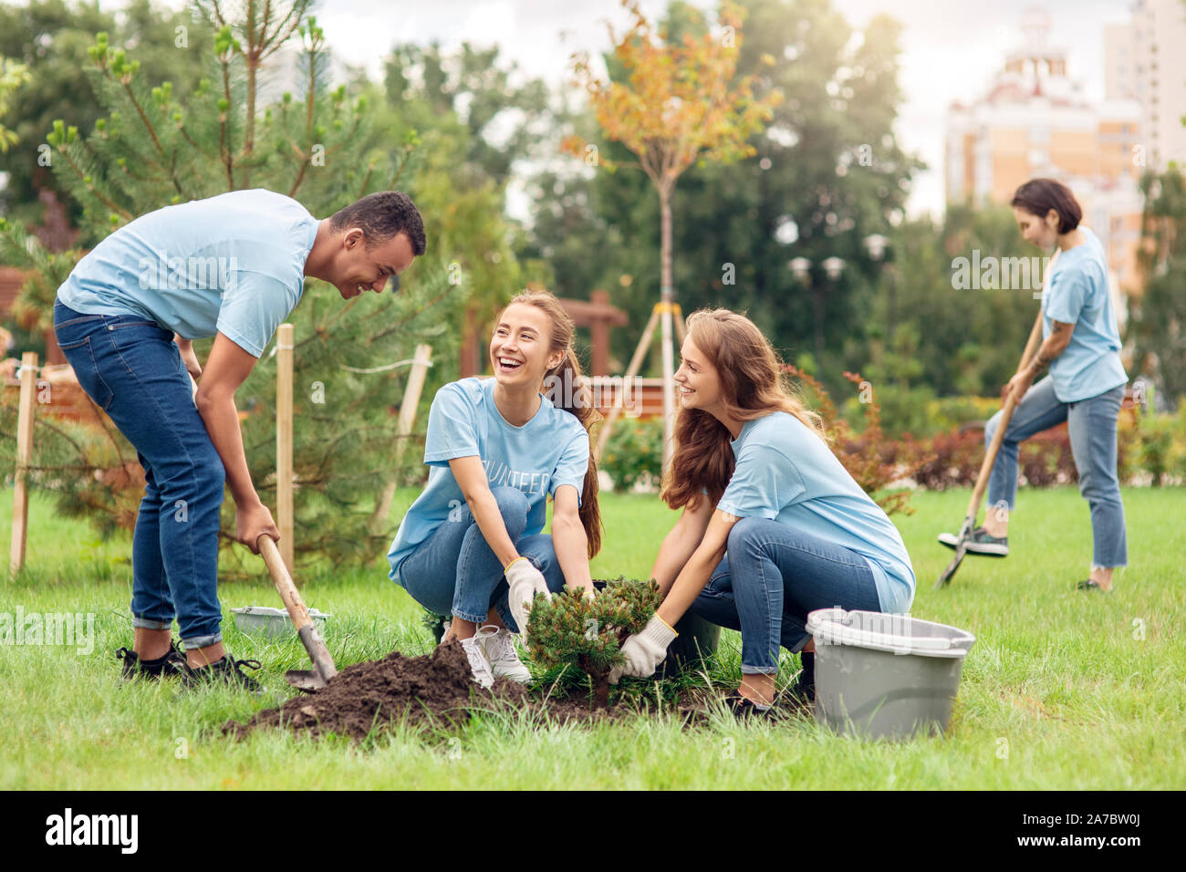 Young people girls and boy volunteers outdoors helping nature planting ...
