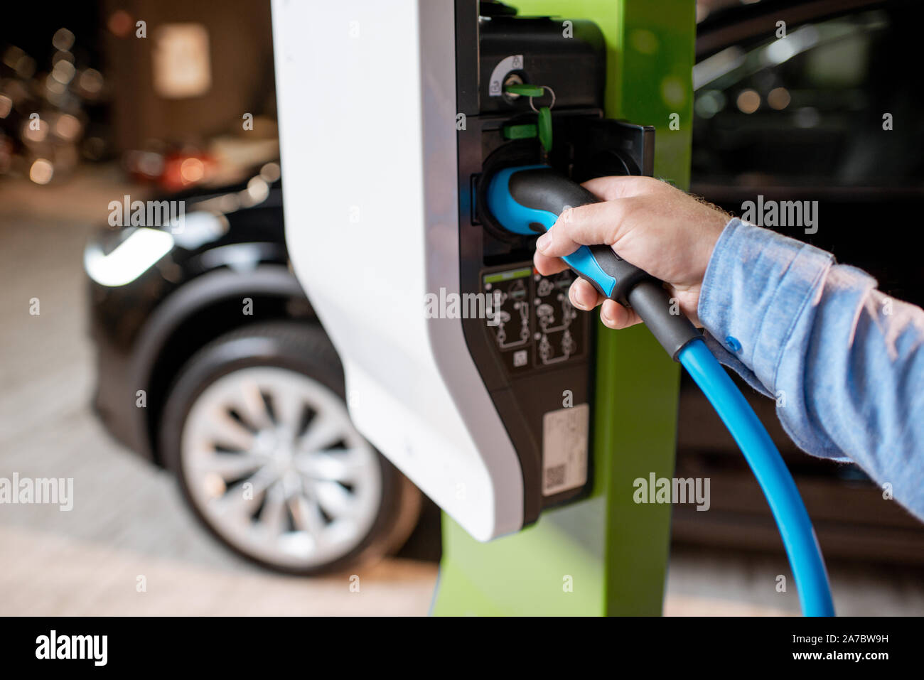 Man plugging cable into the charging station for electric cars at the ...
