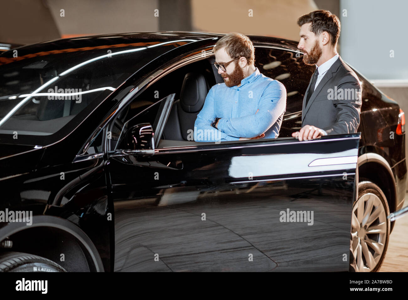 Sales consultant showing to the client vehicle intreior at the car ...