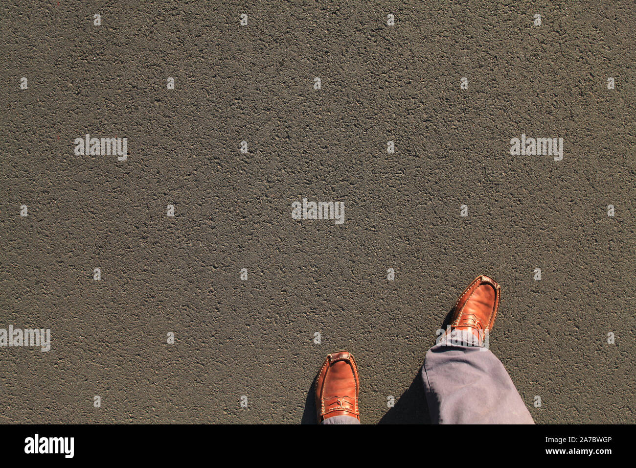 Feet in shoes (loafers or moccasins) on asphalt surface. Detailed ...