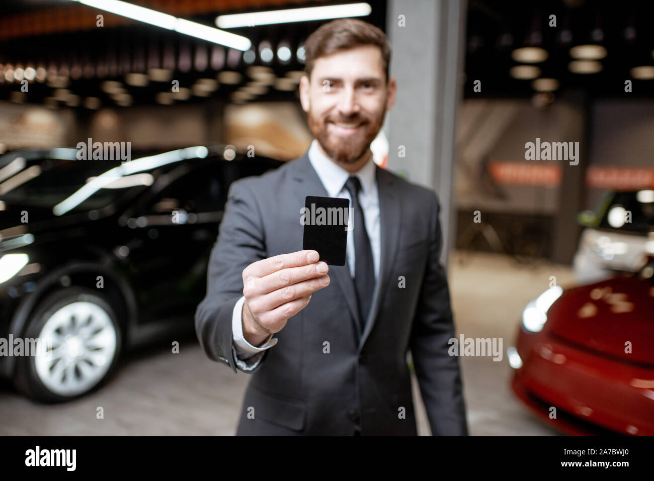 Portrait of an elegant salesman with a card key, selling electric ...