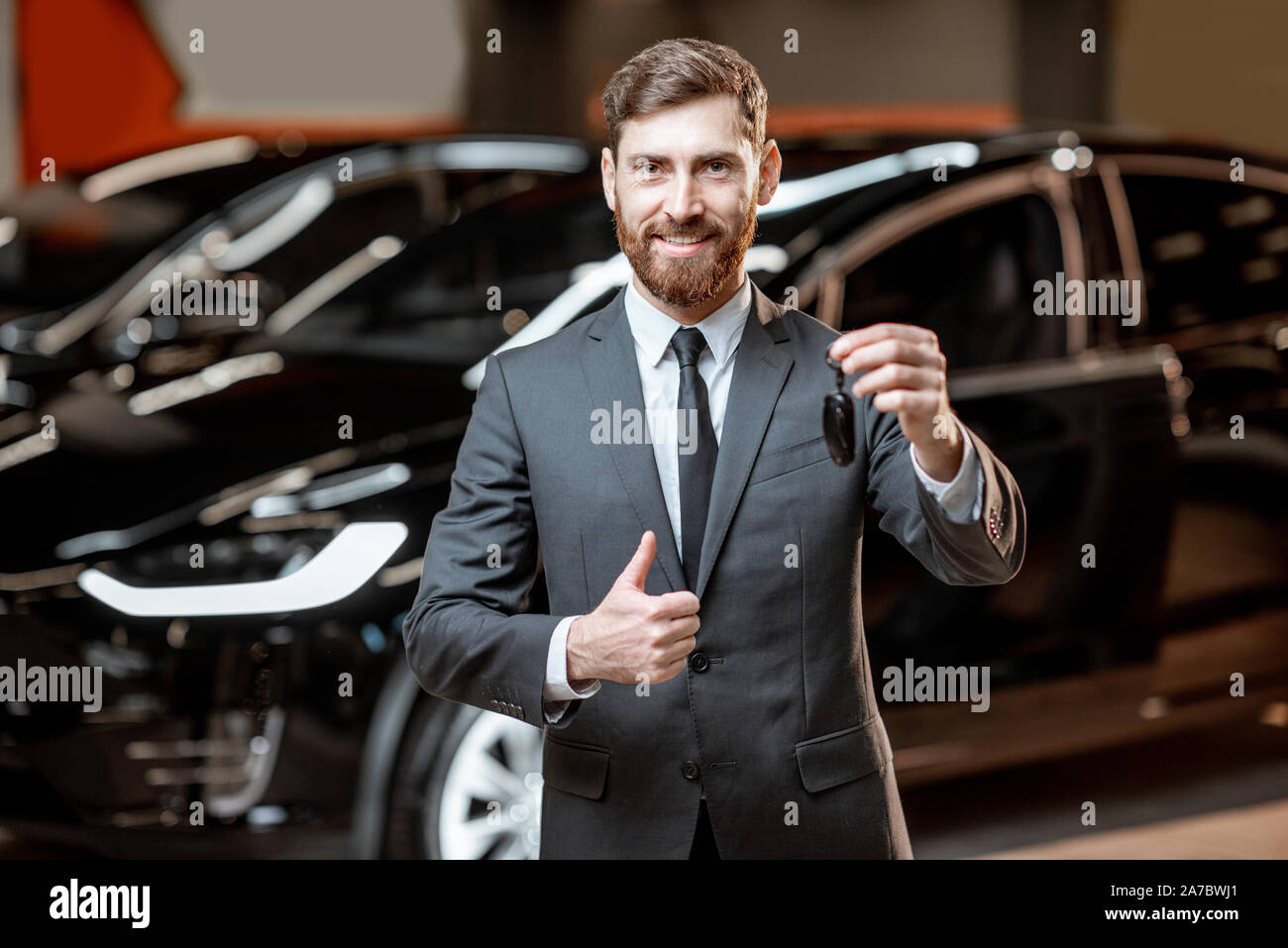 Portrait of an elegant salesman with a car key, selling electric ...