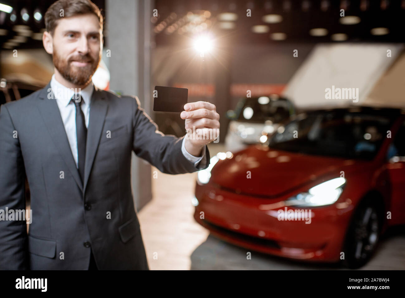 Portrait of an elegant salesman with a car key, selling electric ...