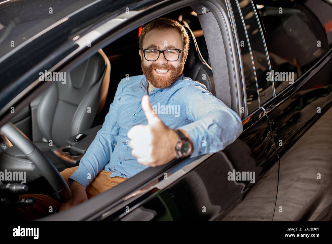 Portrait of a happy man showing OK sign while sitting in the new ...