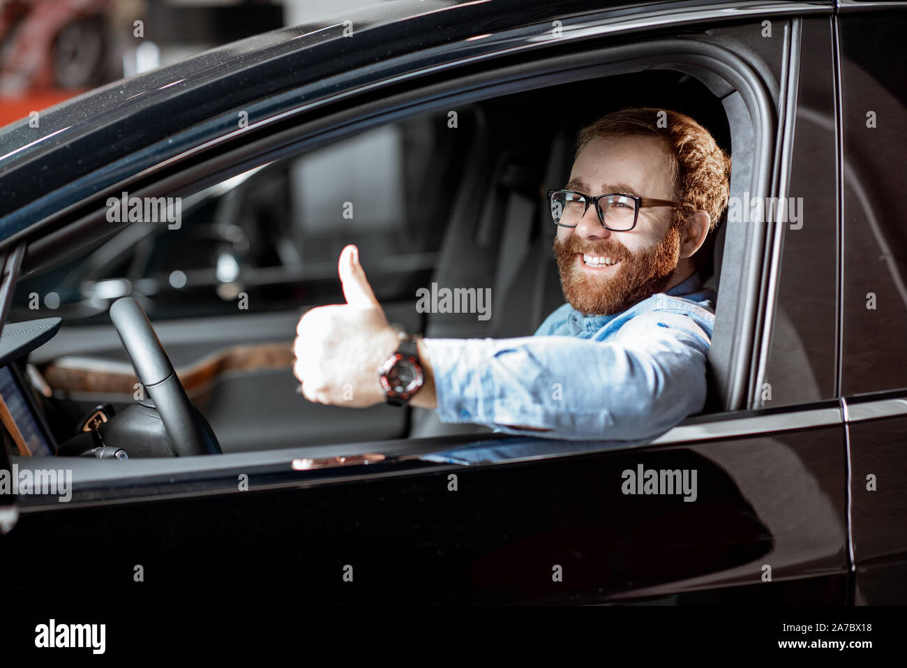 Portrait of a happy man showing OK sign while sitting in the new ...