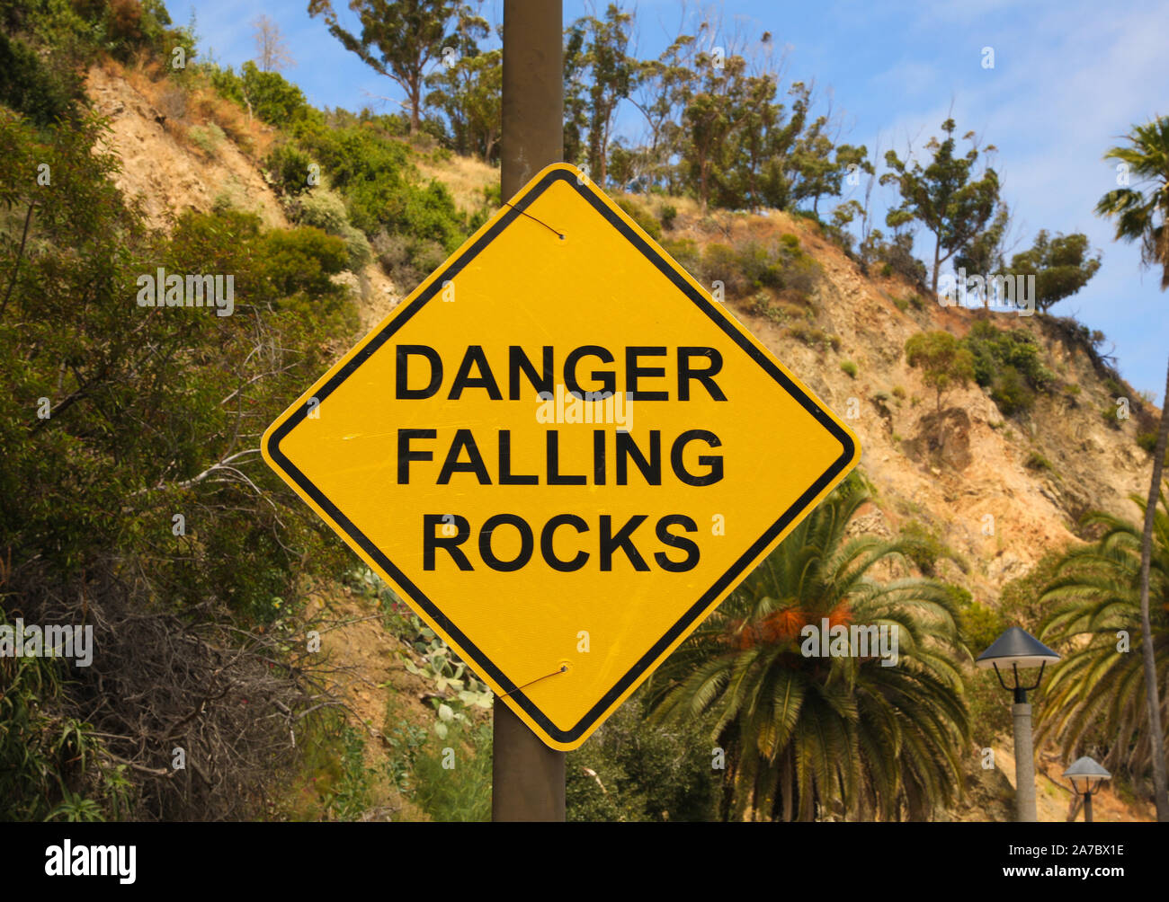 falling rocks Warning sign on a curvy road Stock Photo - Alamy