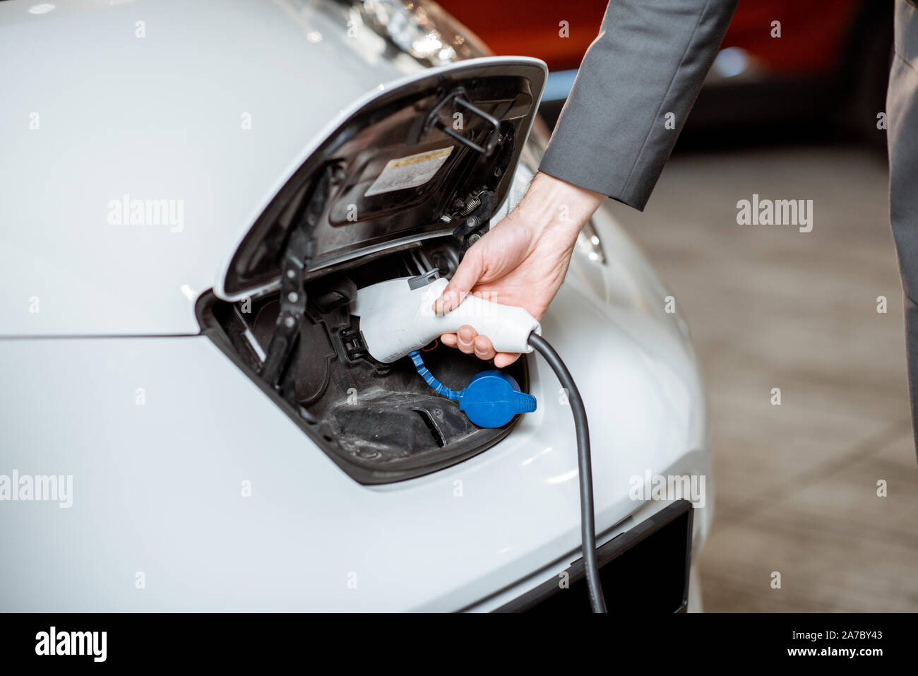 Man plugging charging cable into the car socket, close-up. Electric car ...