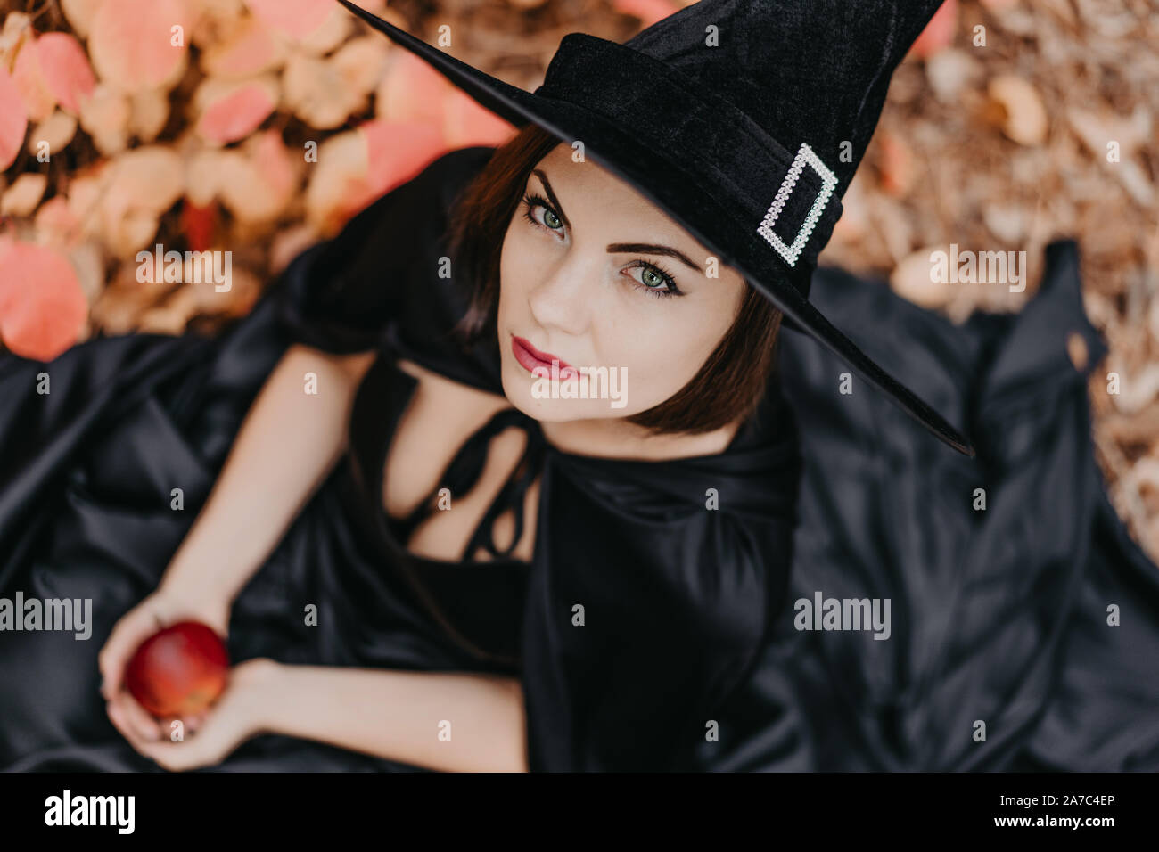 Portrait of woman as witch in black holding red apple as symbol of ...