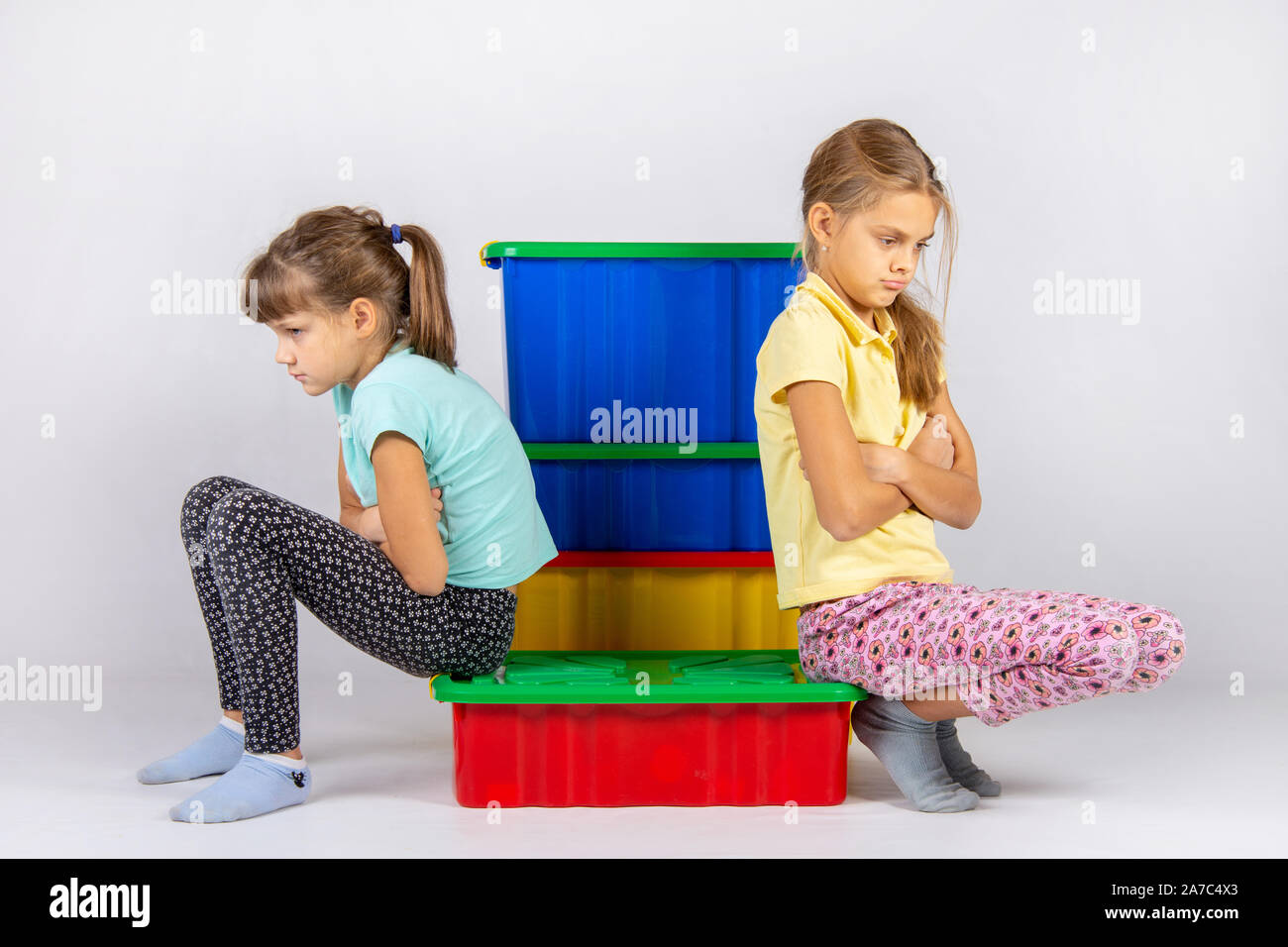 Two girls quarreled, sit on a box and turned away from each other Stock ...