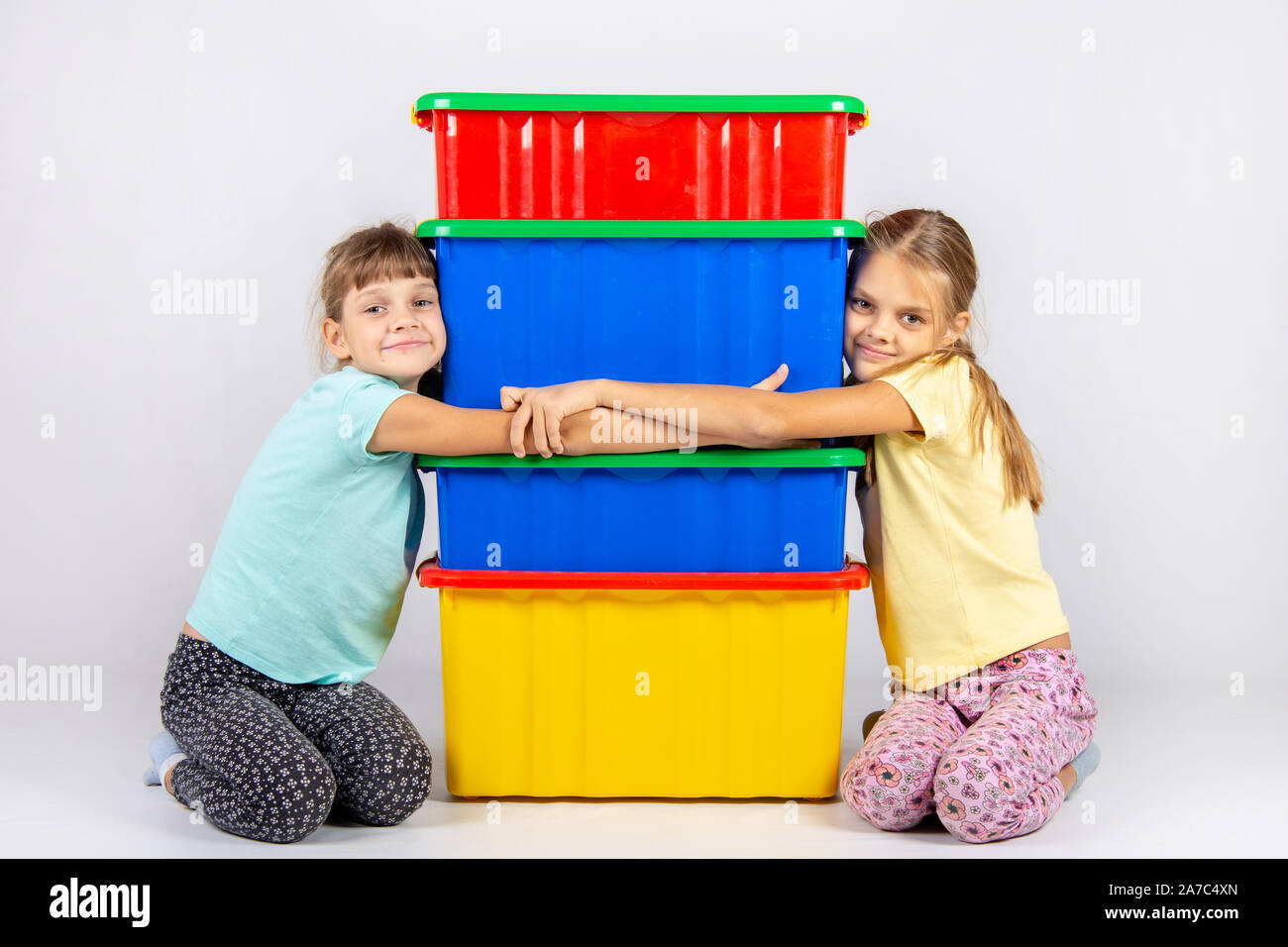 Two girls hug big plastic boxes Stock Photo - Alamy