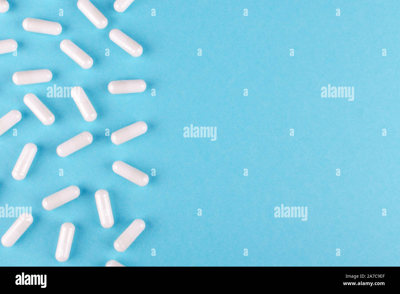 white medicine capsules on blue background with copy space Stock Photo ...
