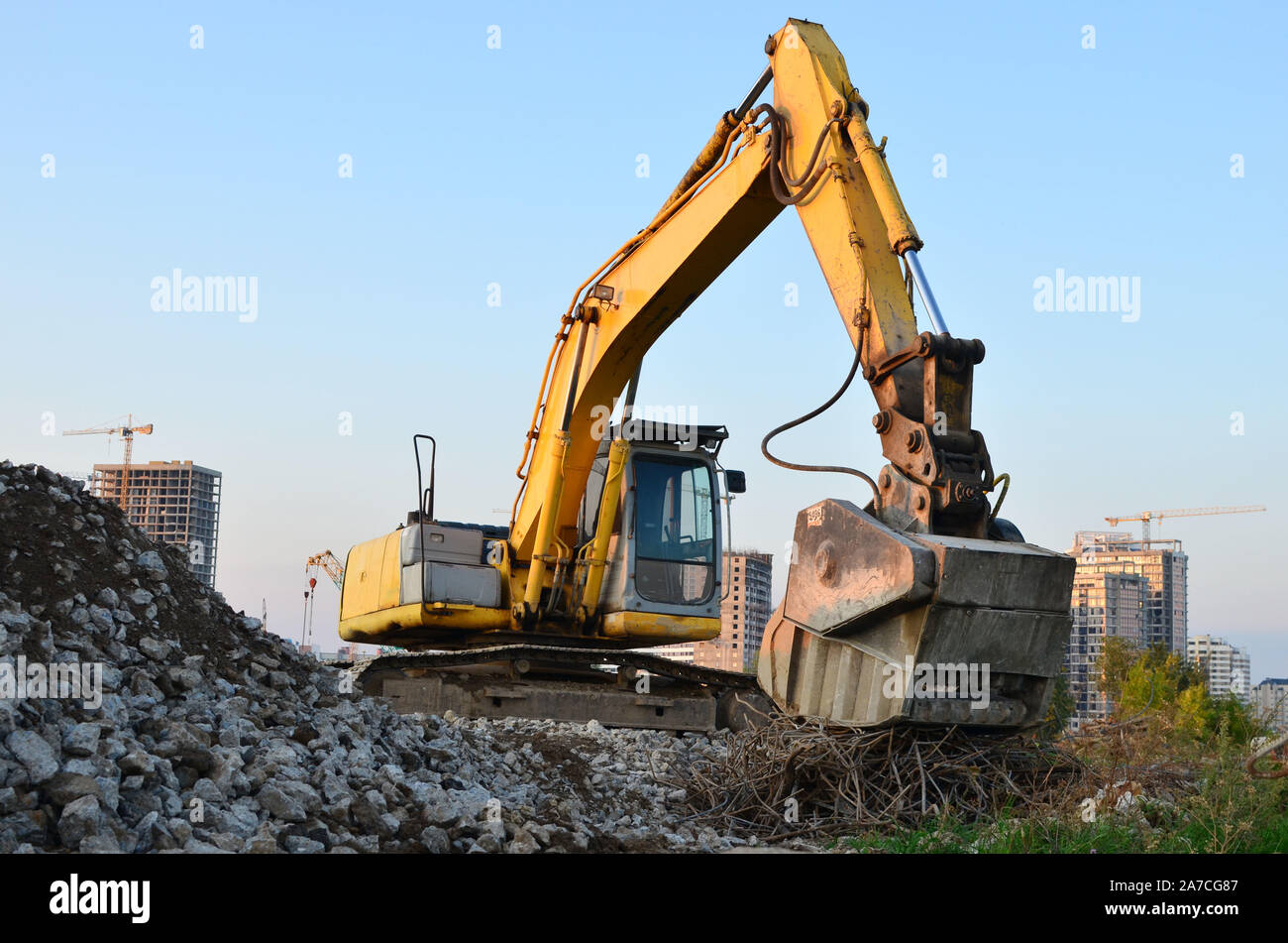 Excavator with crusher bucket for crushing concrete. Construction waste ...