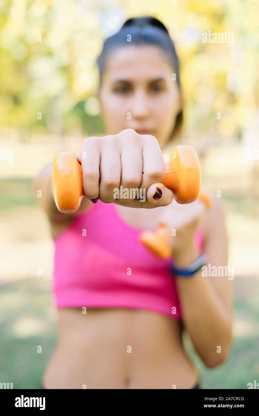 Woman lifting orange weights in the park Stock Photo - Alamy
