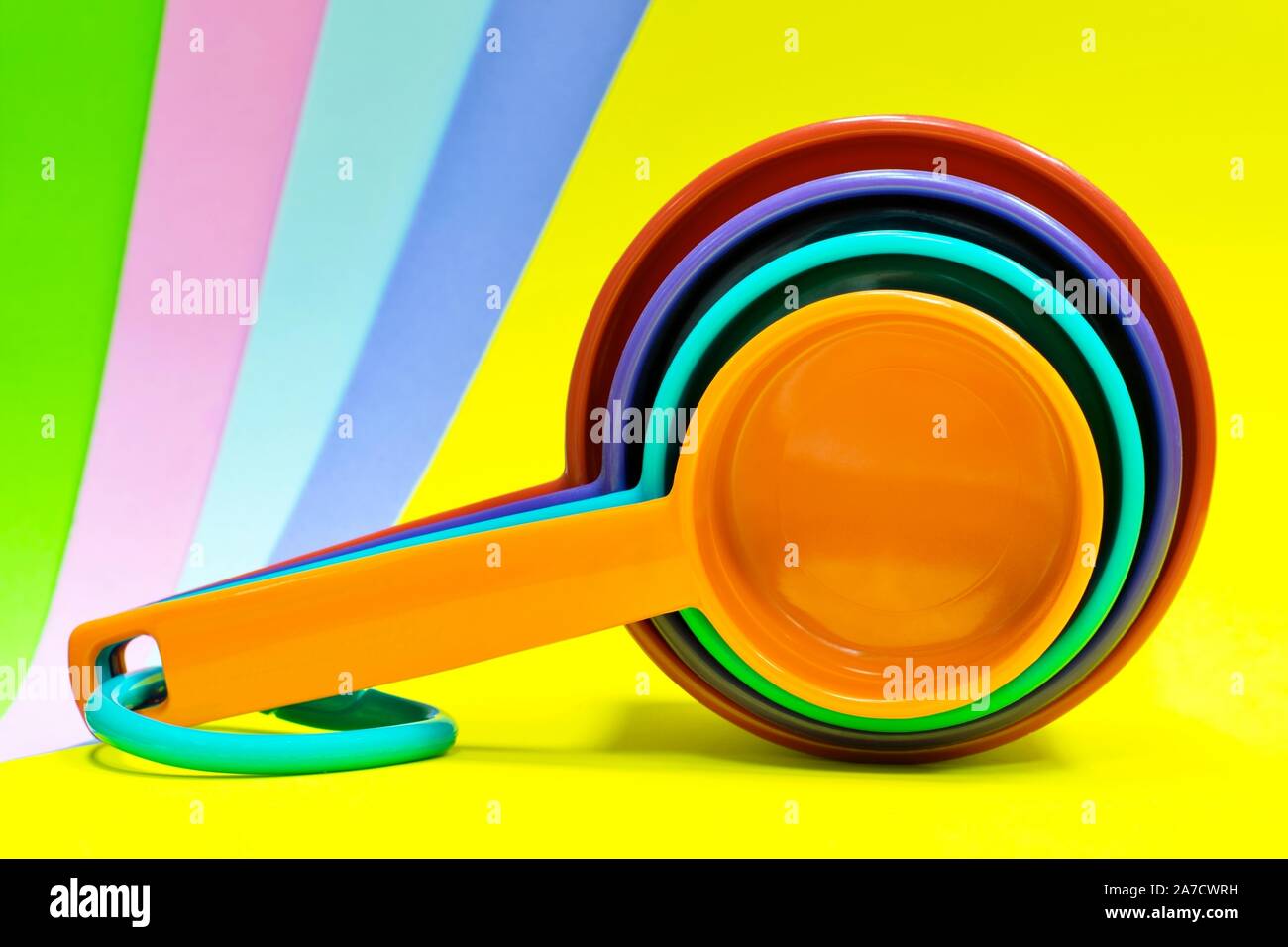 Plastic measuring cups with various bright colors isolated against a ...