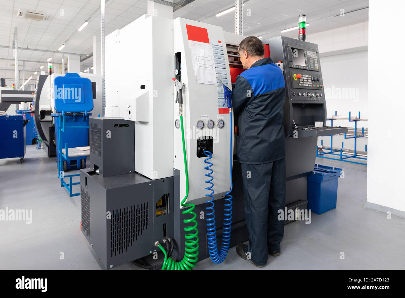 Engineer of metal processing equipment before panel with buttons and ...
