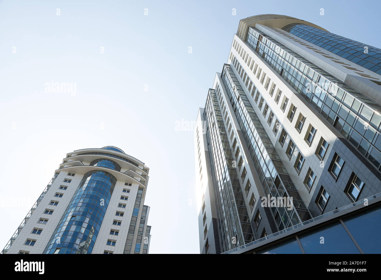 Bottom view of two high apartment buildings at blue sky background ...