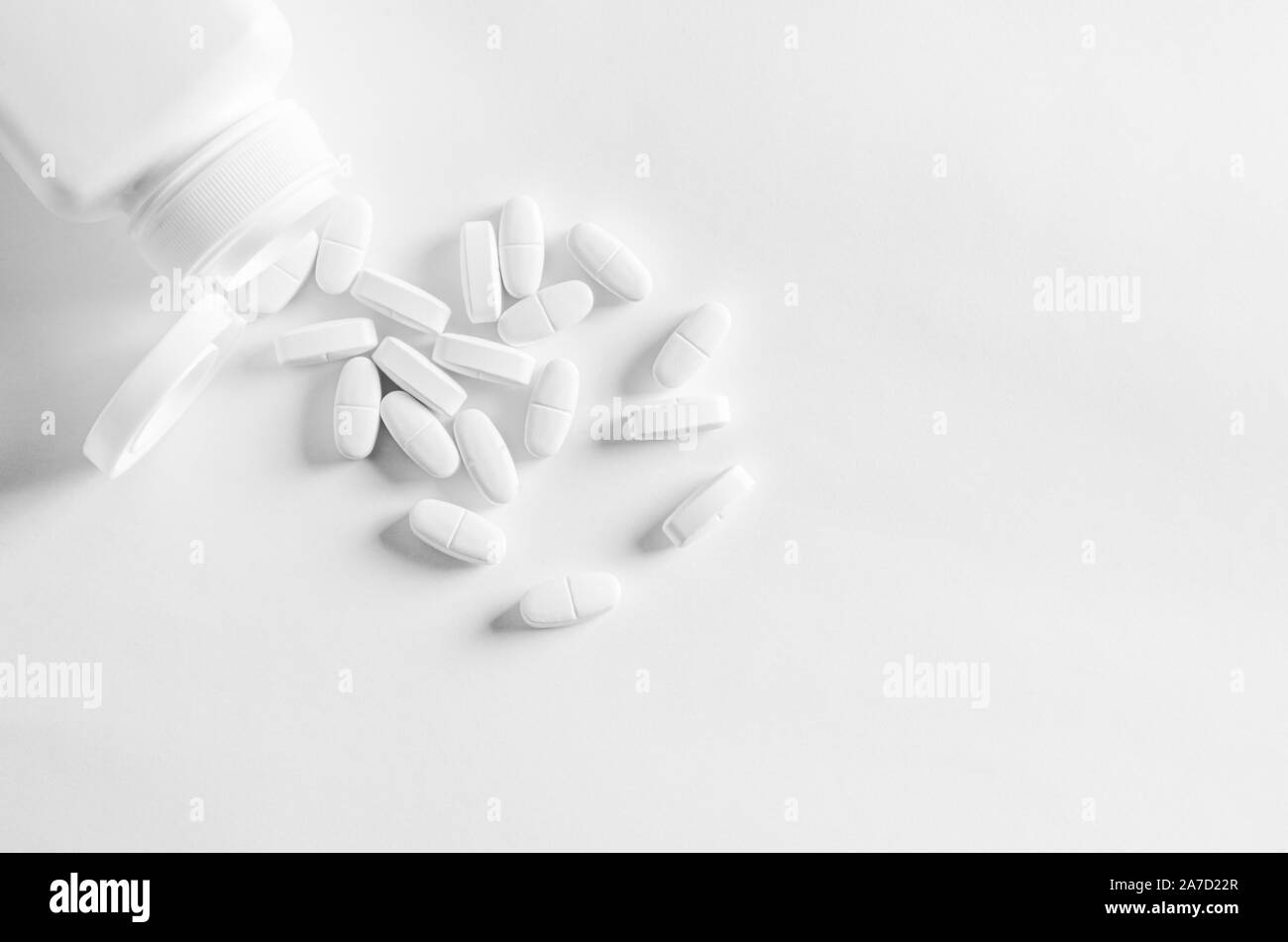 A white plastic container with white tablets lies on a white background ...