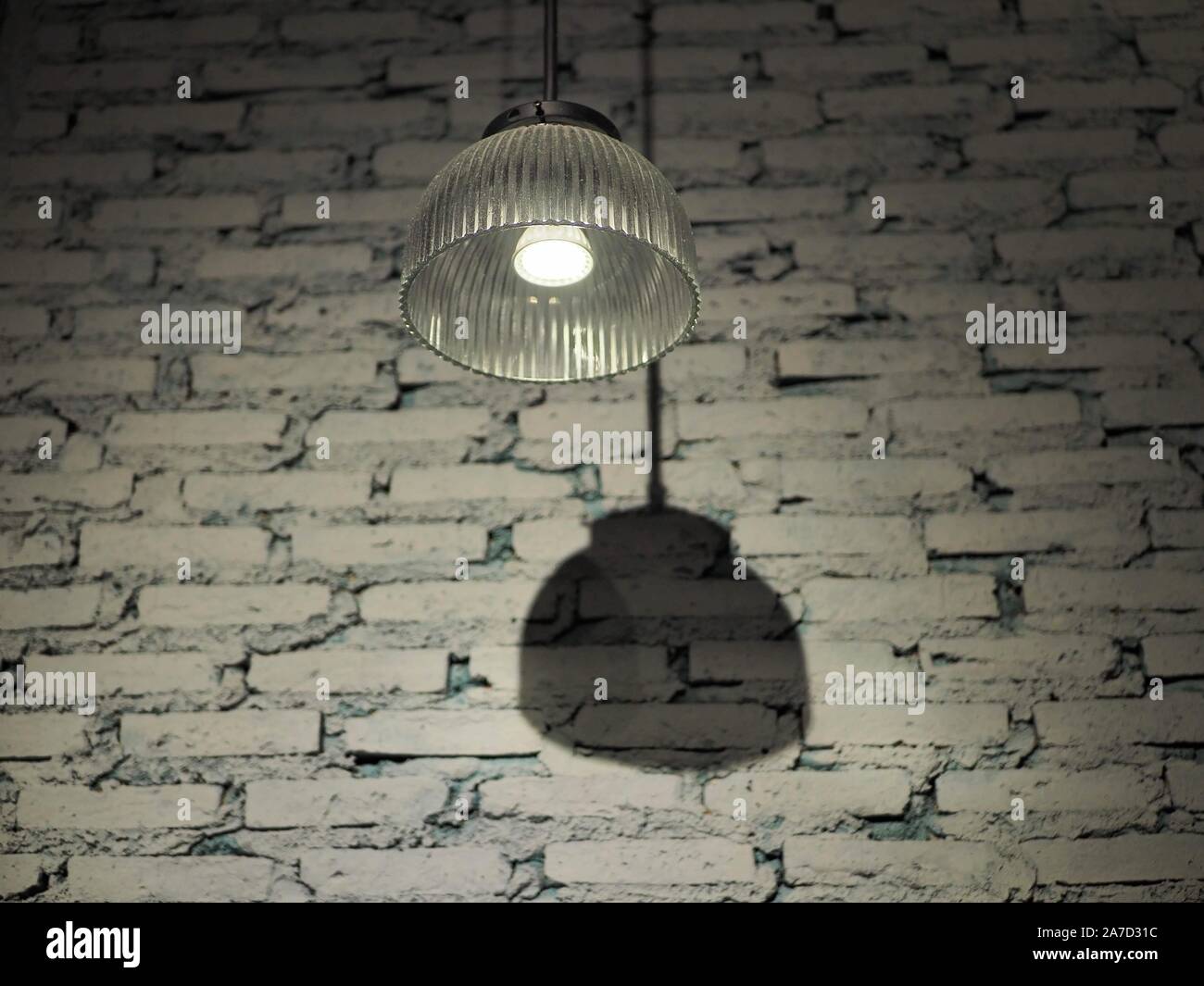 Light up lamp in front of brick wall throwing shadow. Lamp and shadow ...