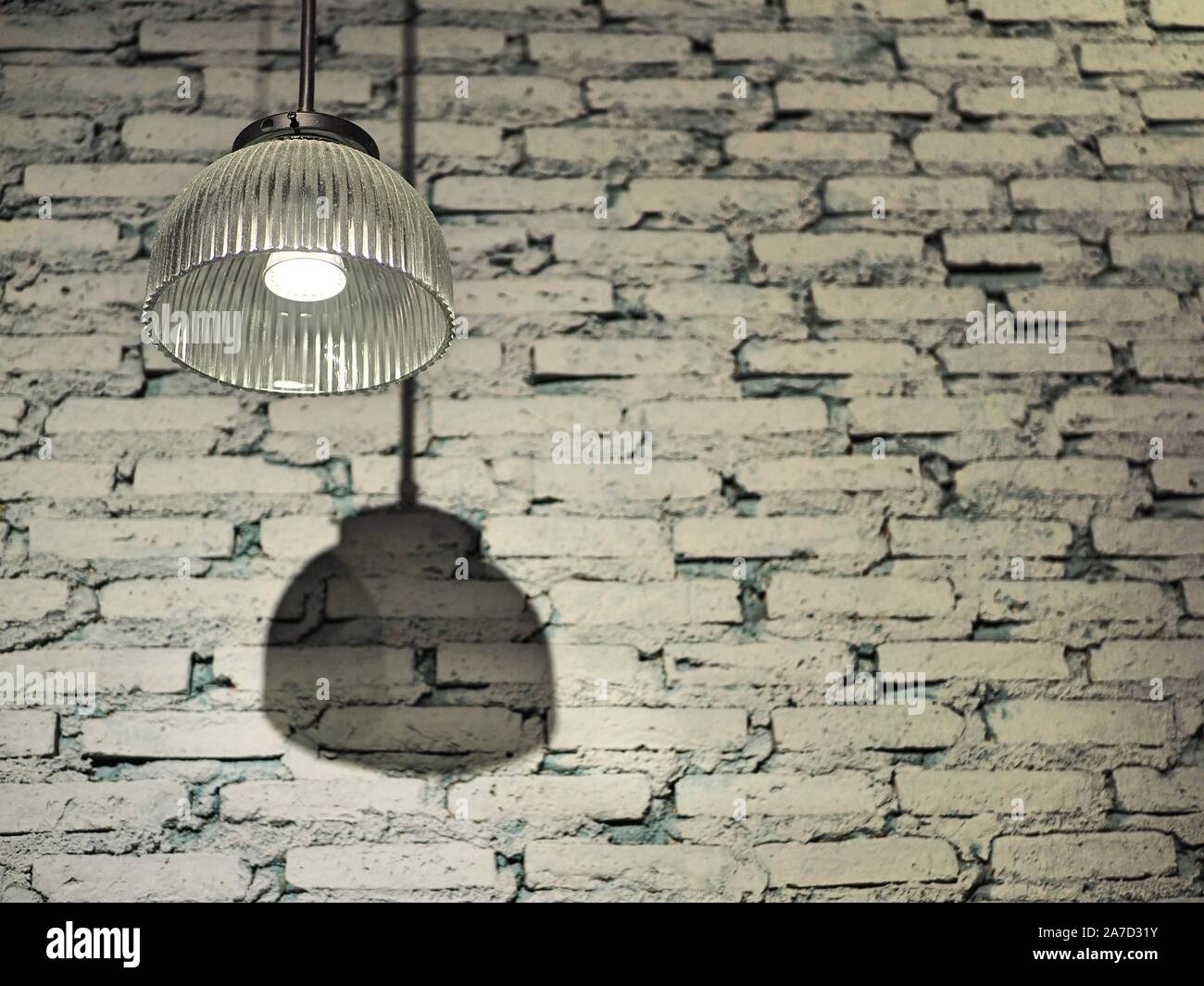 Light up lamp in front of brick wall throwing shadow. Lamp and shadow ...