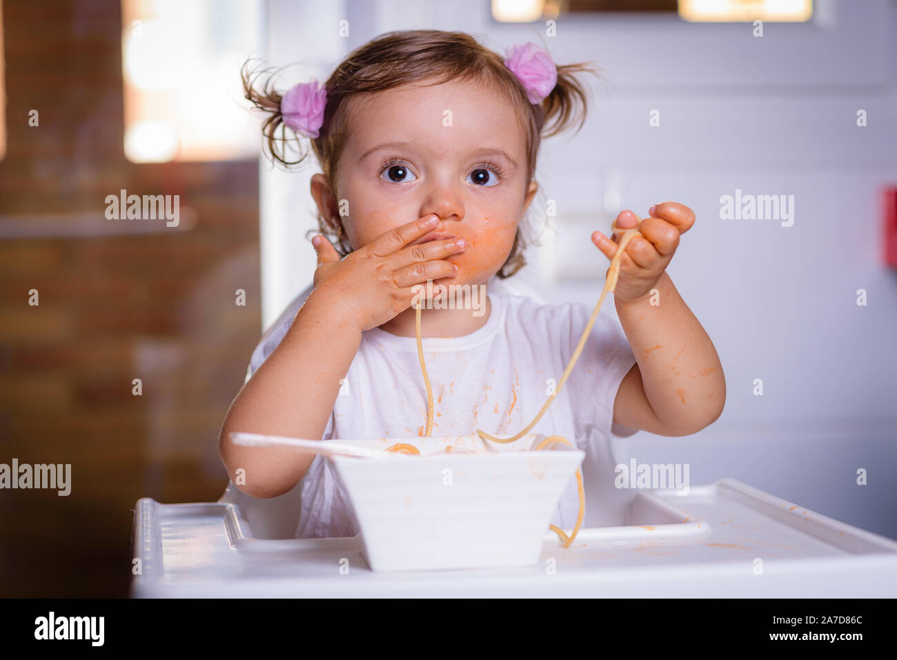 Adorable little girl eating spaghetti with Bolognese sauce with her ...