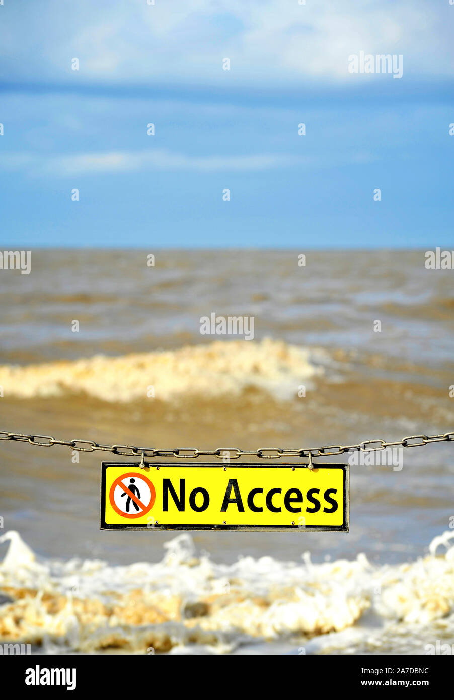 Bright yellow no access sign in front of rough sea at high tide Stock ...