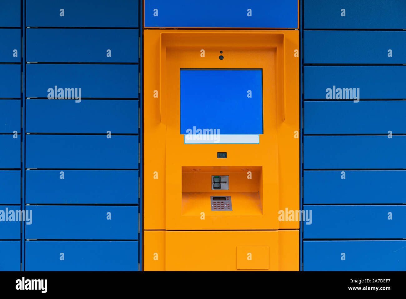 Orange cashpoint minibank with blank copyspace screen on blue panel ...
