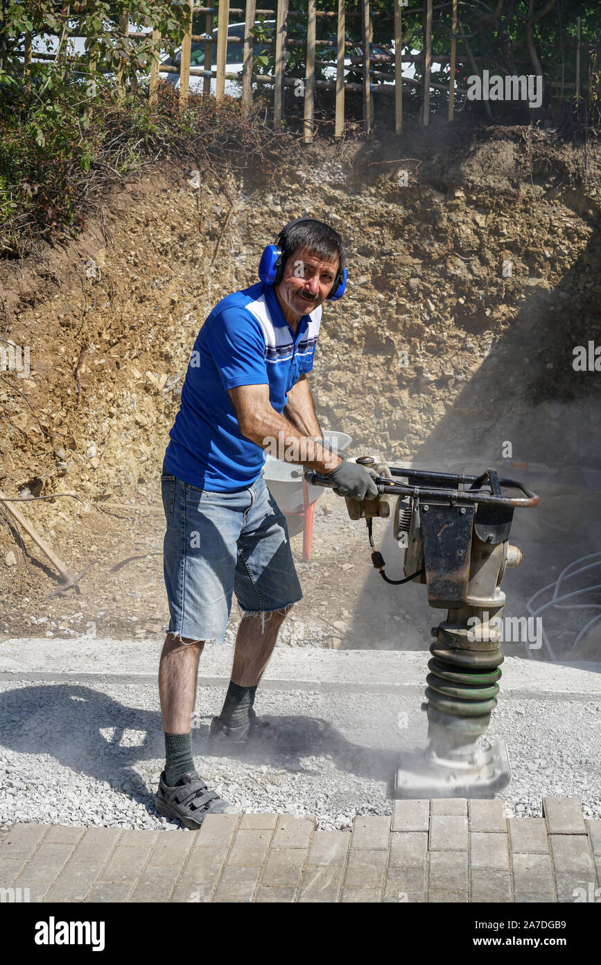 Construction worker compacting soil using compactor. Work with tamping ...
