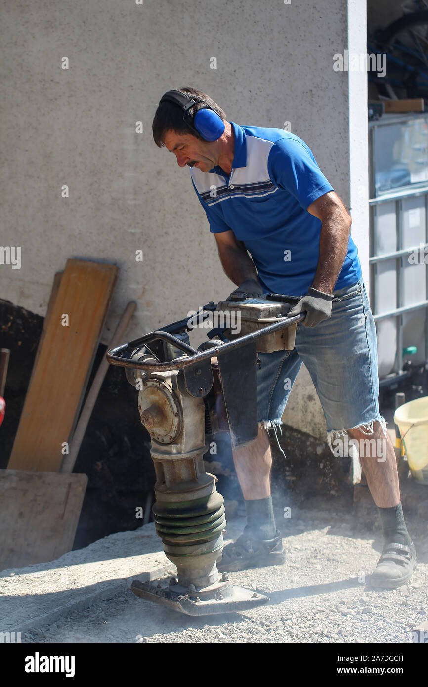Construction worker compacting soil using compactor. Work with tamping ...