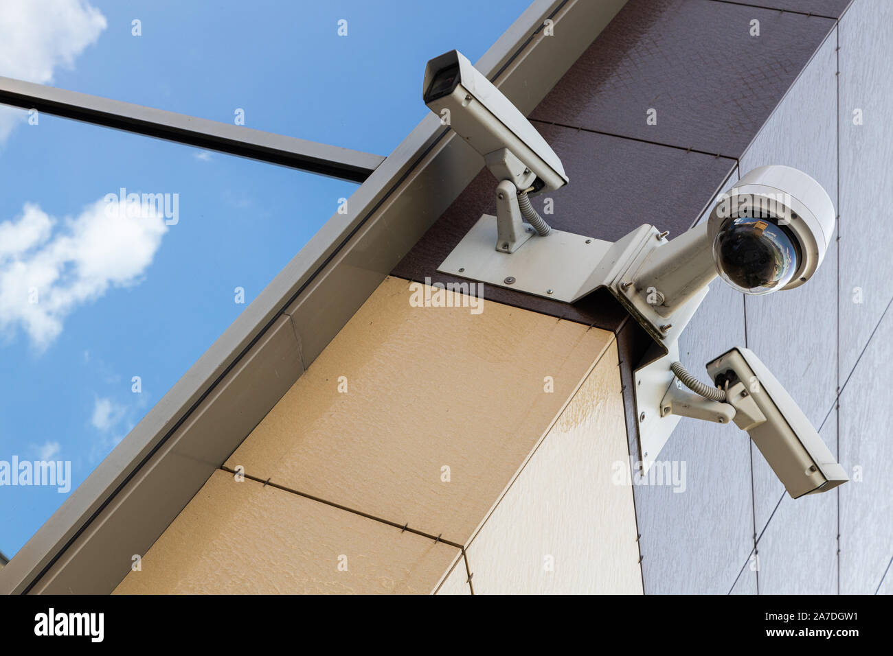 Diagonal bottom view of three white surveillance cameras on office ...