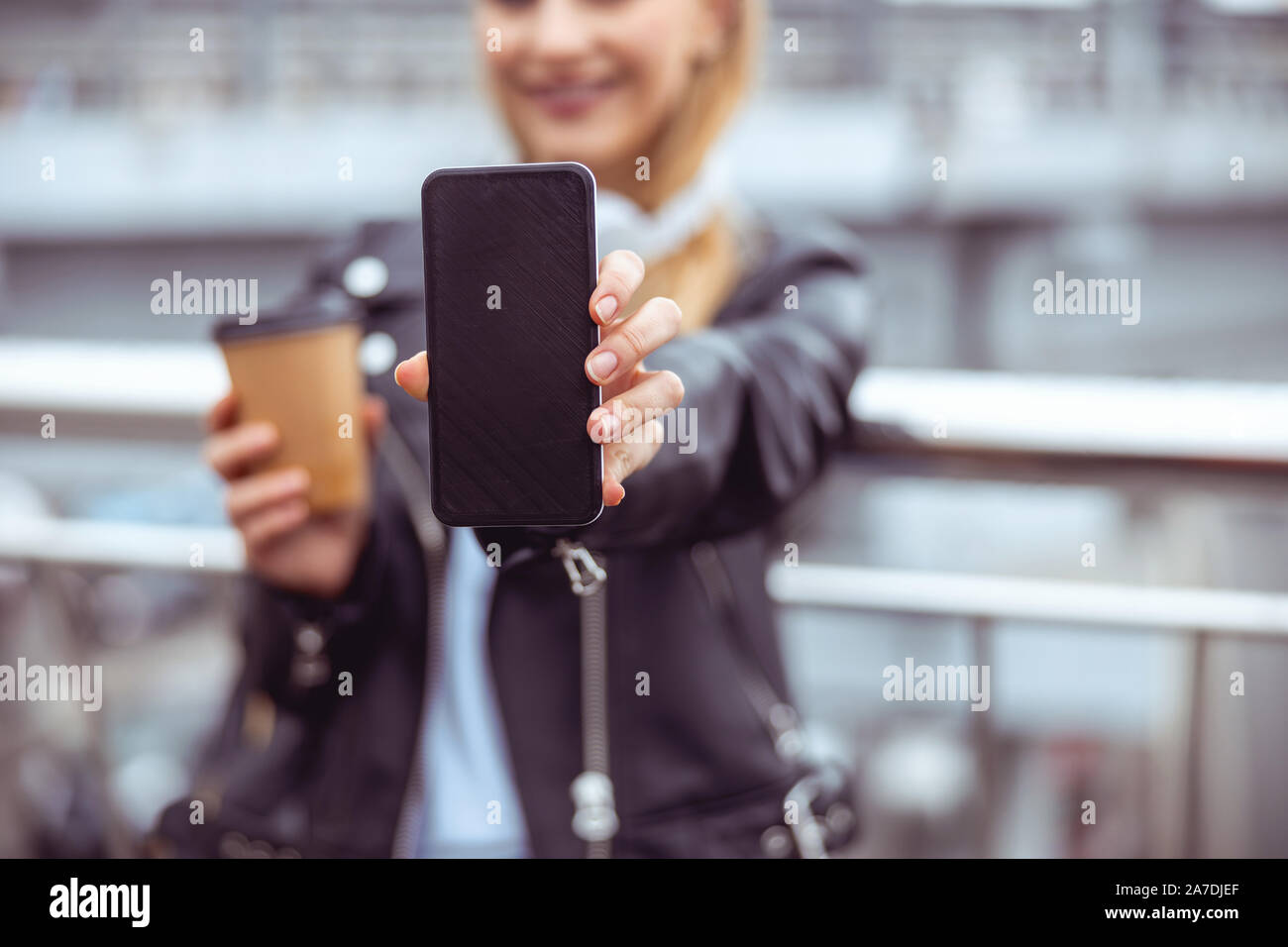 Smiling female holding a gadget in front of her Stock Photo - Alamy