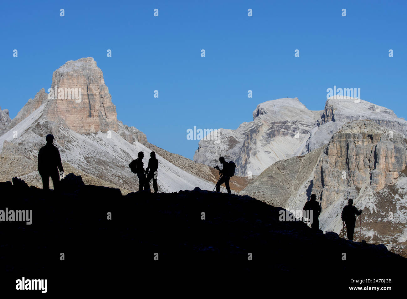 Mountain walkers silhouetted against Torre dei Scarperi ...