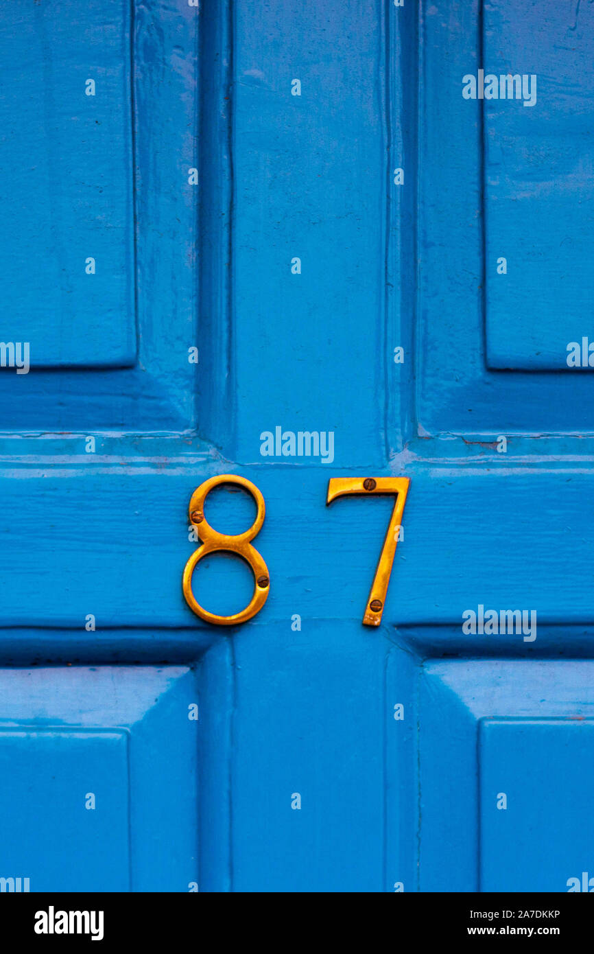 Bronze house number 87 on a bright blue wooden front door Stock Photo ...