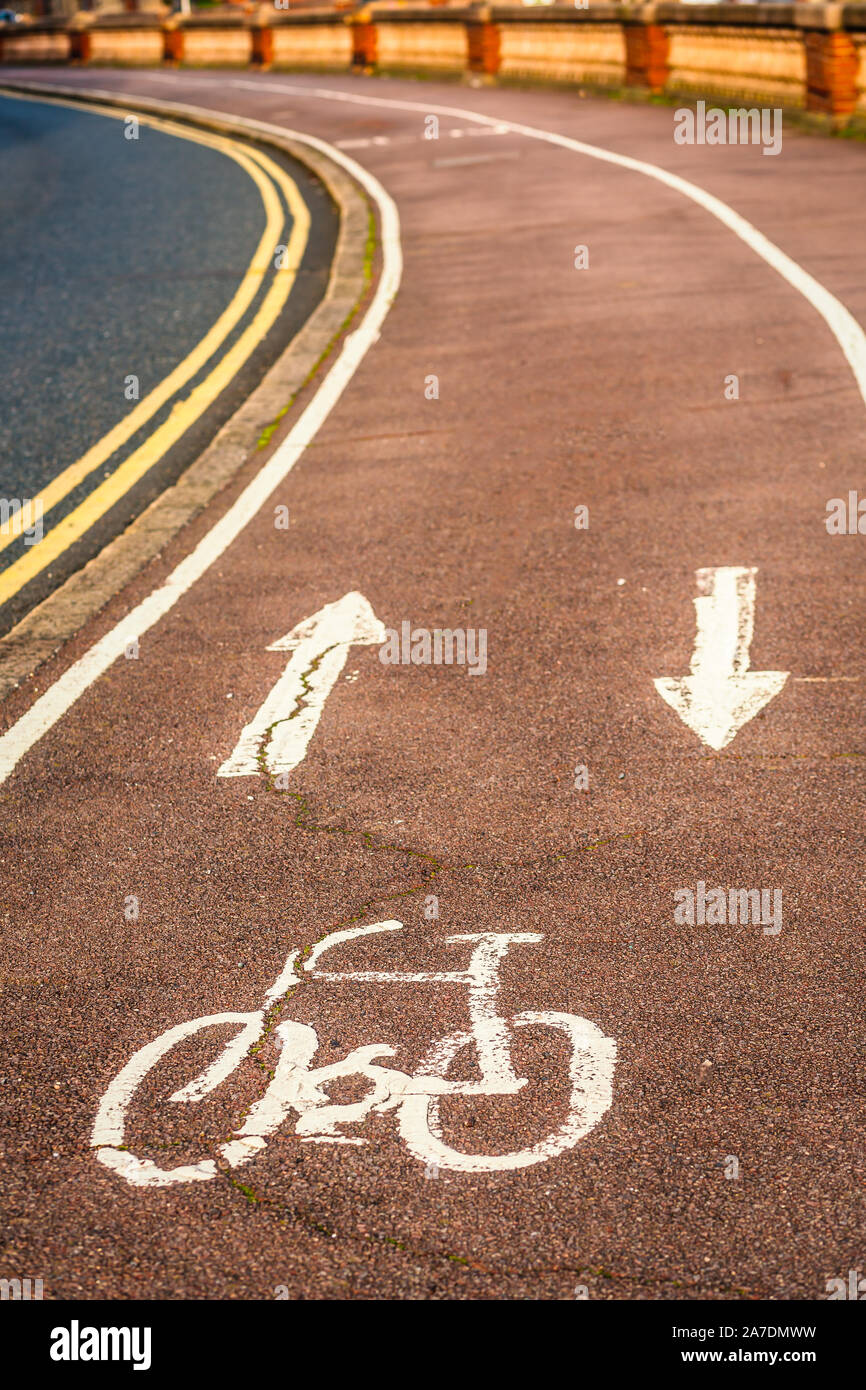 Bicycle icon painted in white paint on to a cycle path with two arrows ...